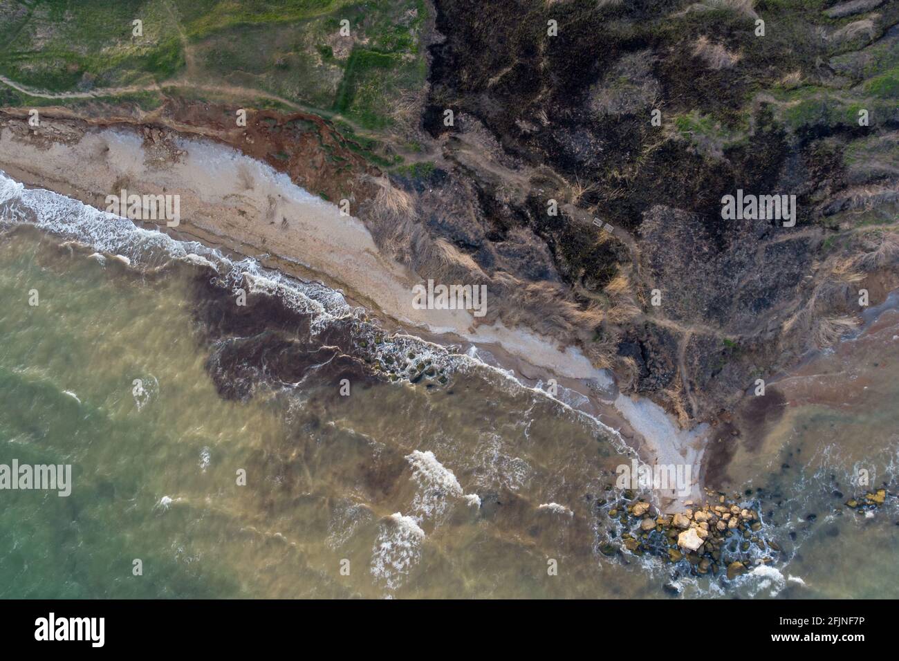 Steep sea shore and surf. Sea water muddy with sand after storm and ...