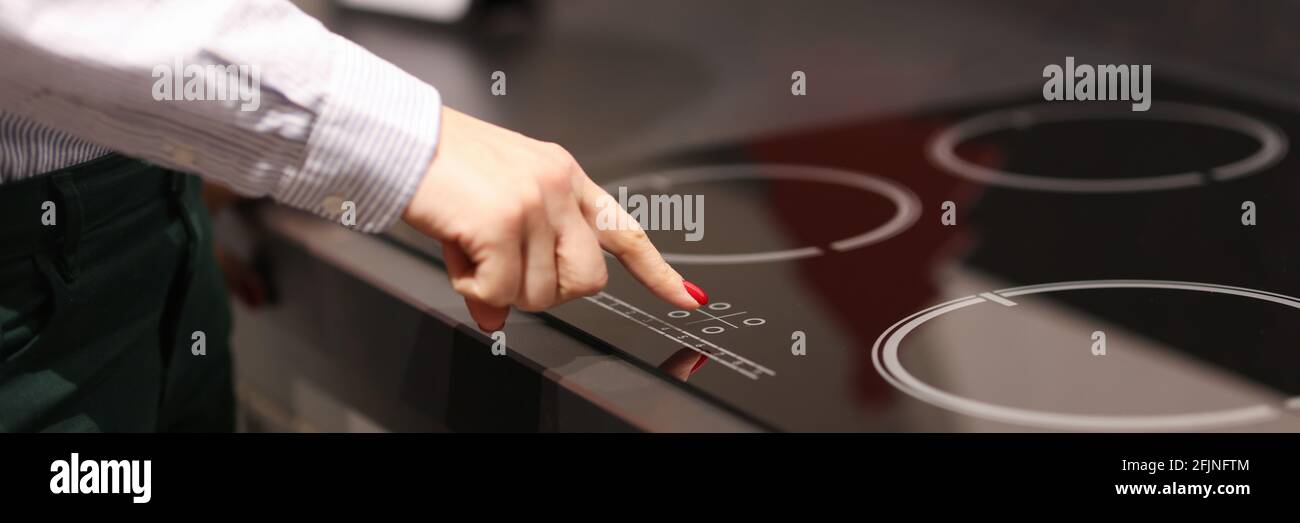 Female finger presses button on touch electric stove Stock Photo - Alamy