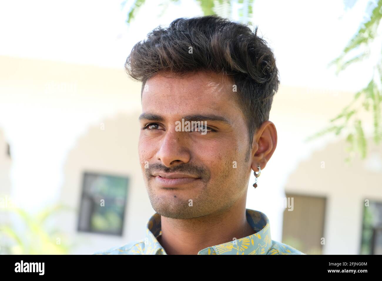 A portrait of a young handsome Indian male standing outdoors at daytime ...