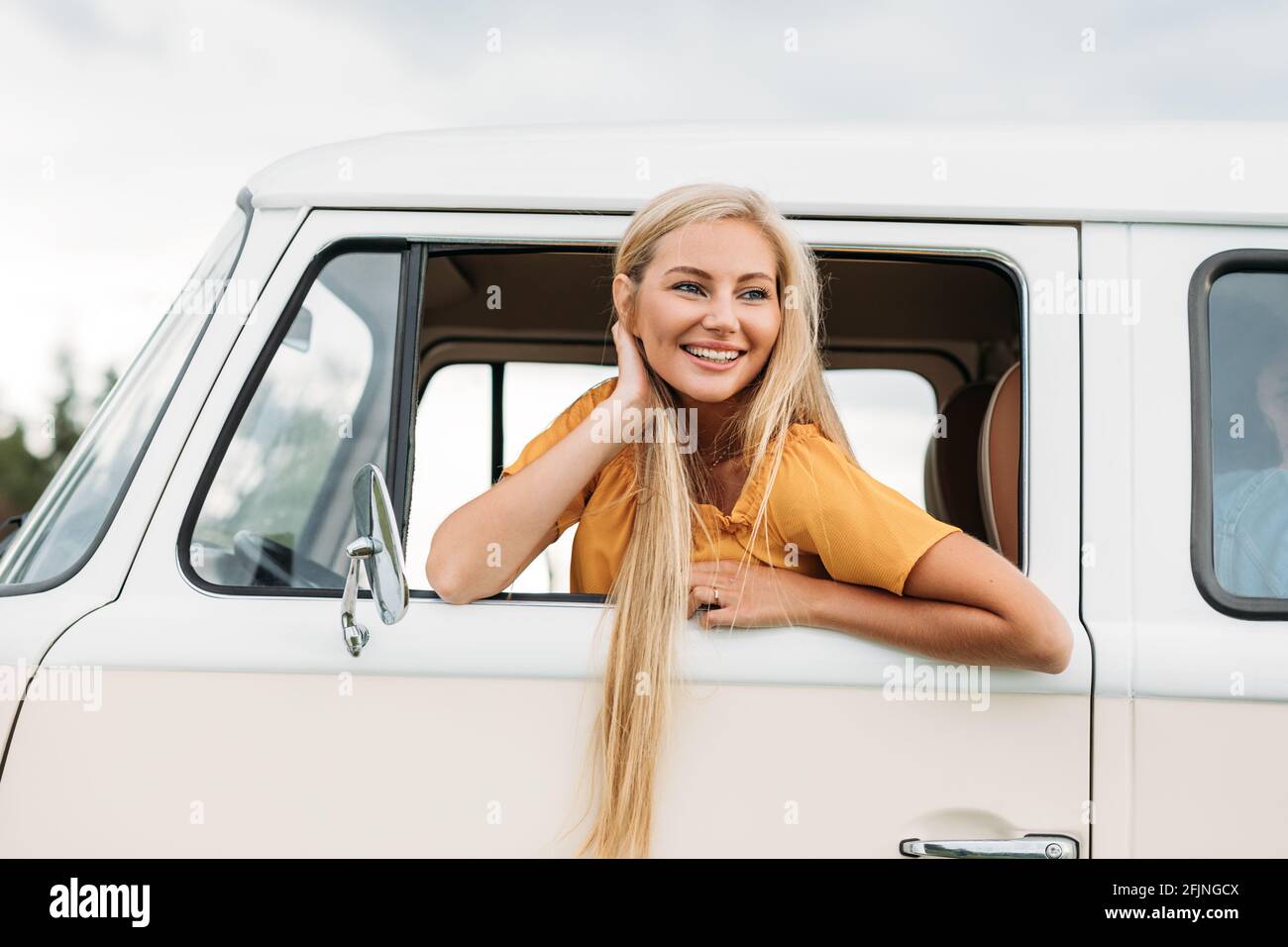 Happy woman with long hair looks out of car window while sitting on ...
