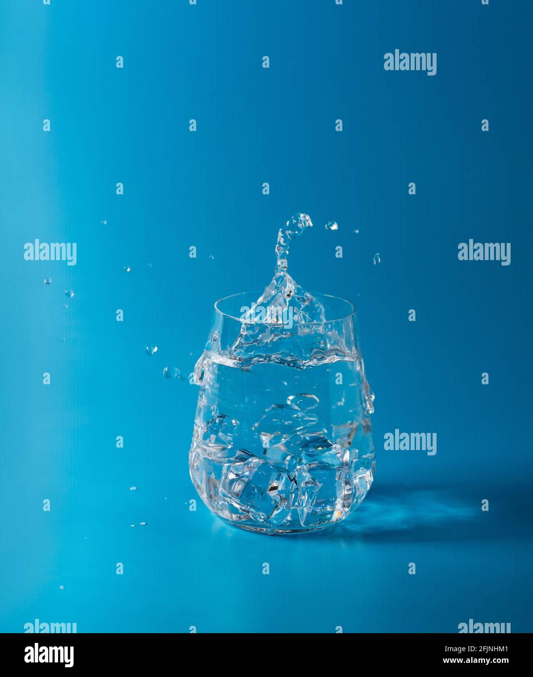 Crystal clear water with ice in a clear glass glass on a blue ...