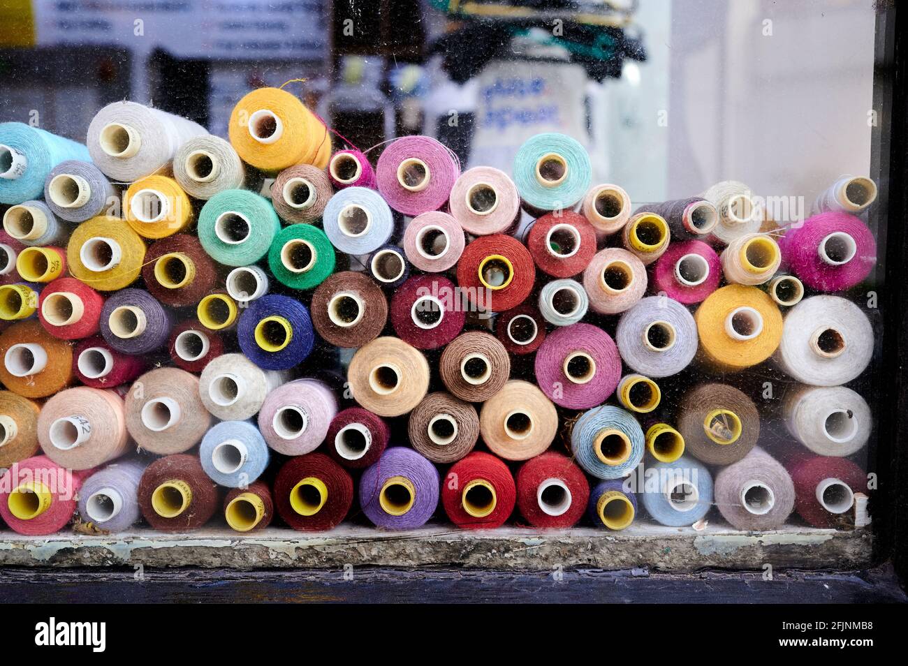 Colored coloured cotton bobbins through glass window Stock Photo - Alamy