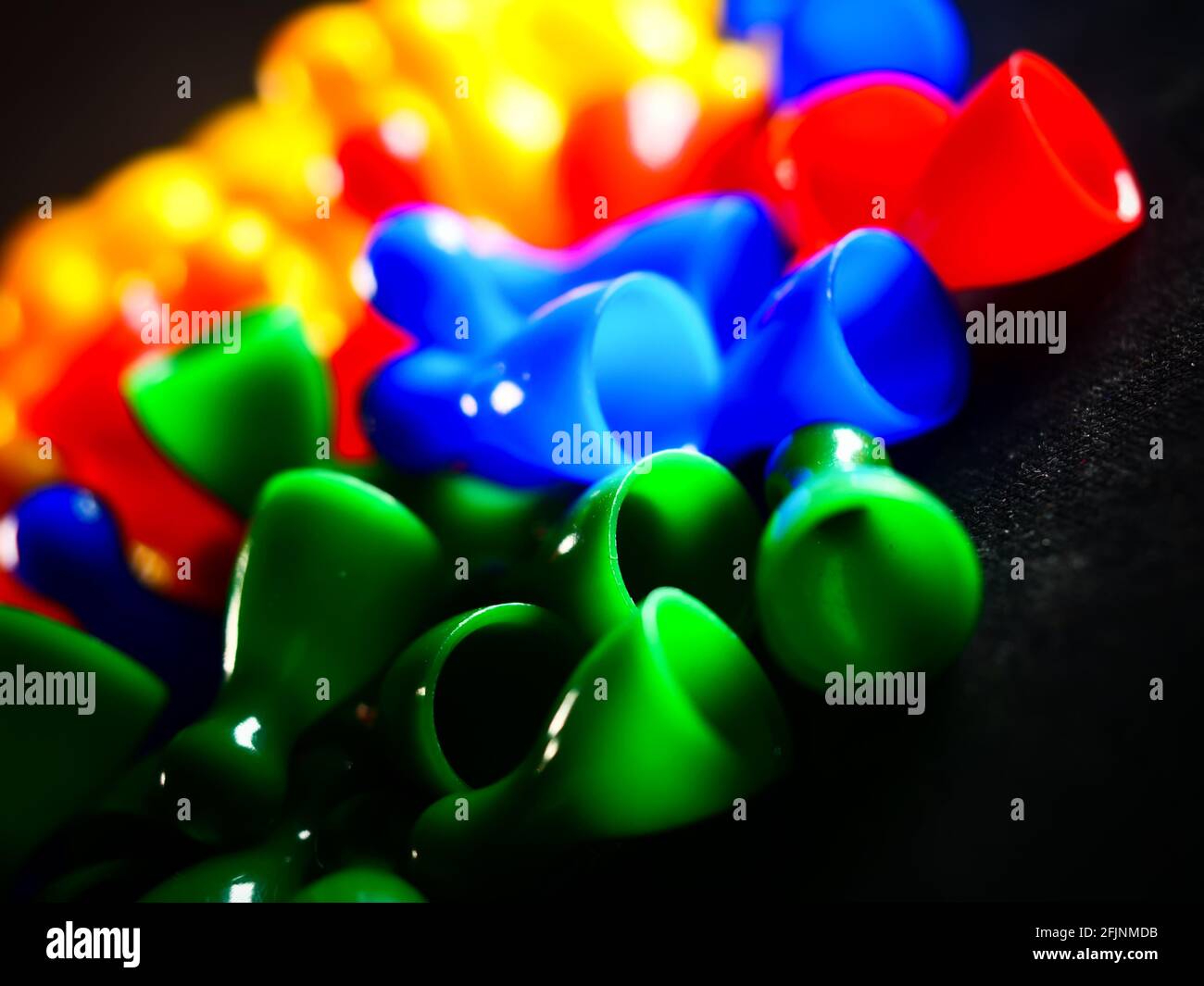 A studio shot of colorful monopoly plastic chips on black background ...
