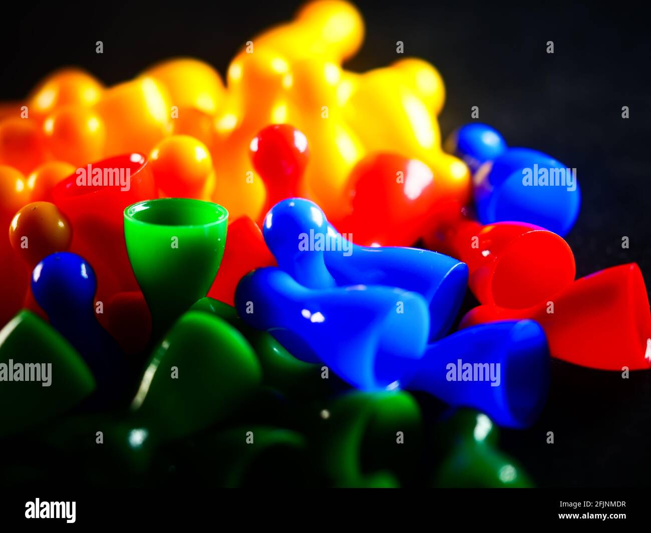 A studio shot of colorful monopoly plastic chips on black background ...