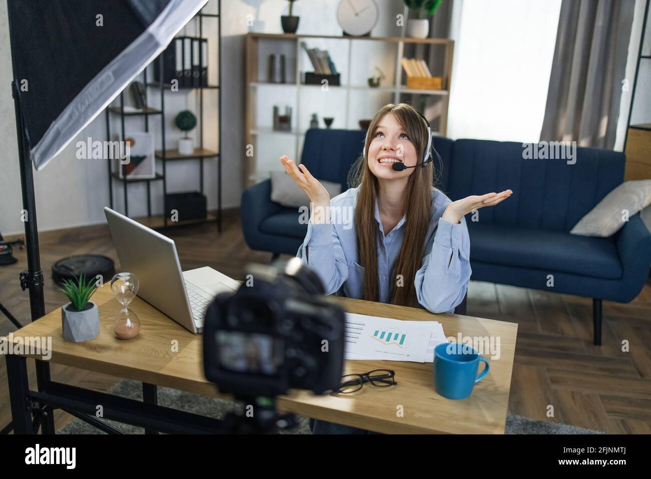 Charming caucasian woman in headset making live broadcast using modern ...