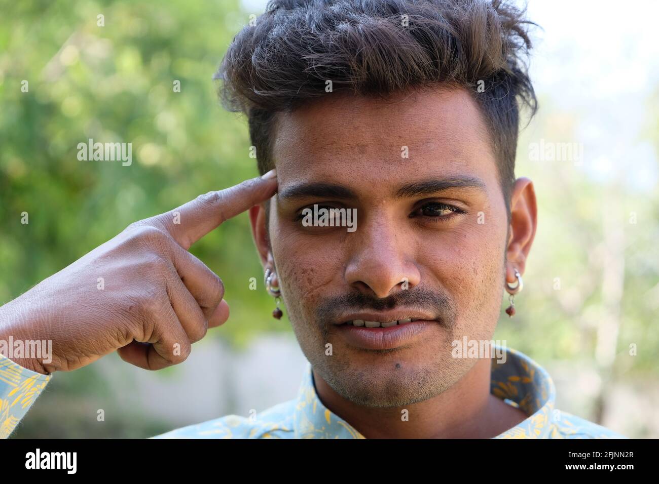 A portrait of a young handsome Indian male standing in a park with the ...