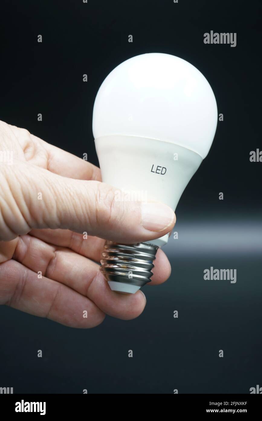 Man's hand holding LED light bulb. Close-up. Isolated on black Stock ...
