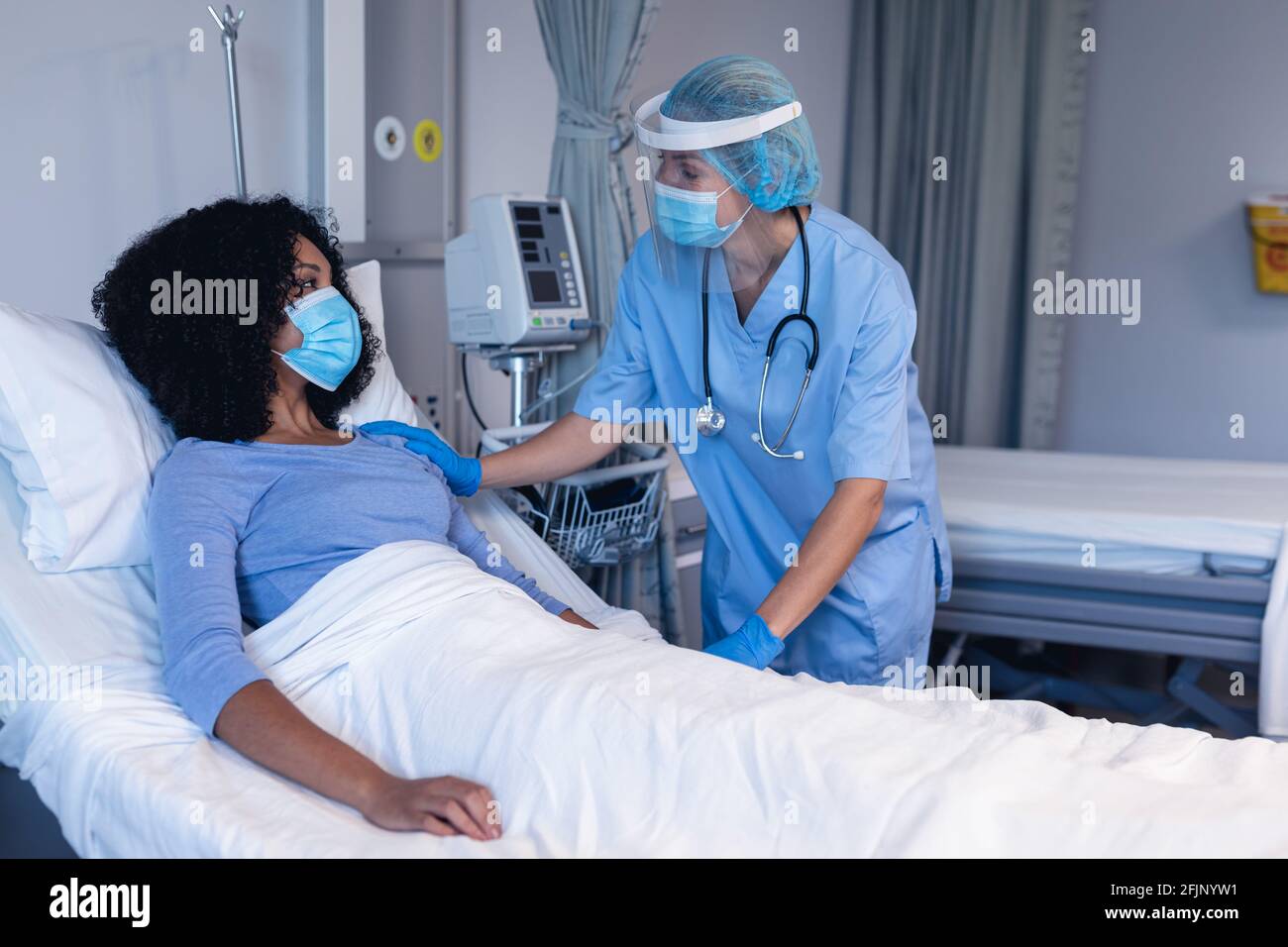 Caucasian female doctor in hospital in face mask consoling female ...