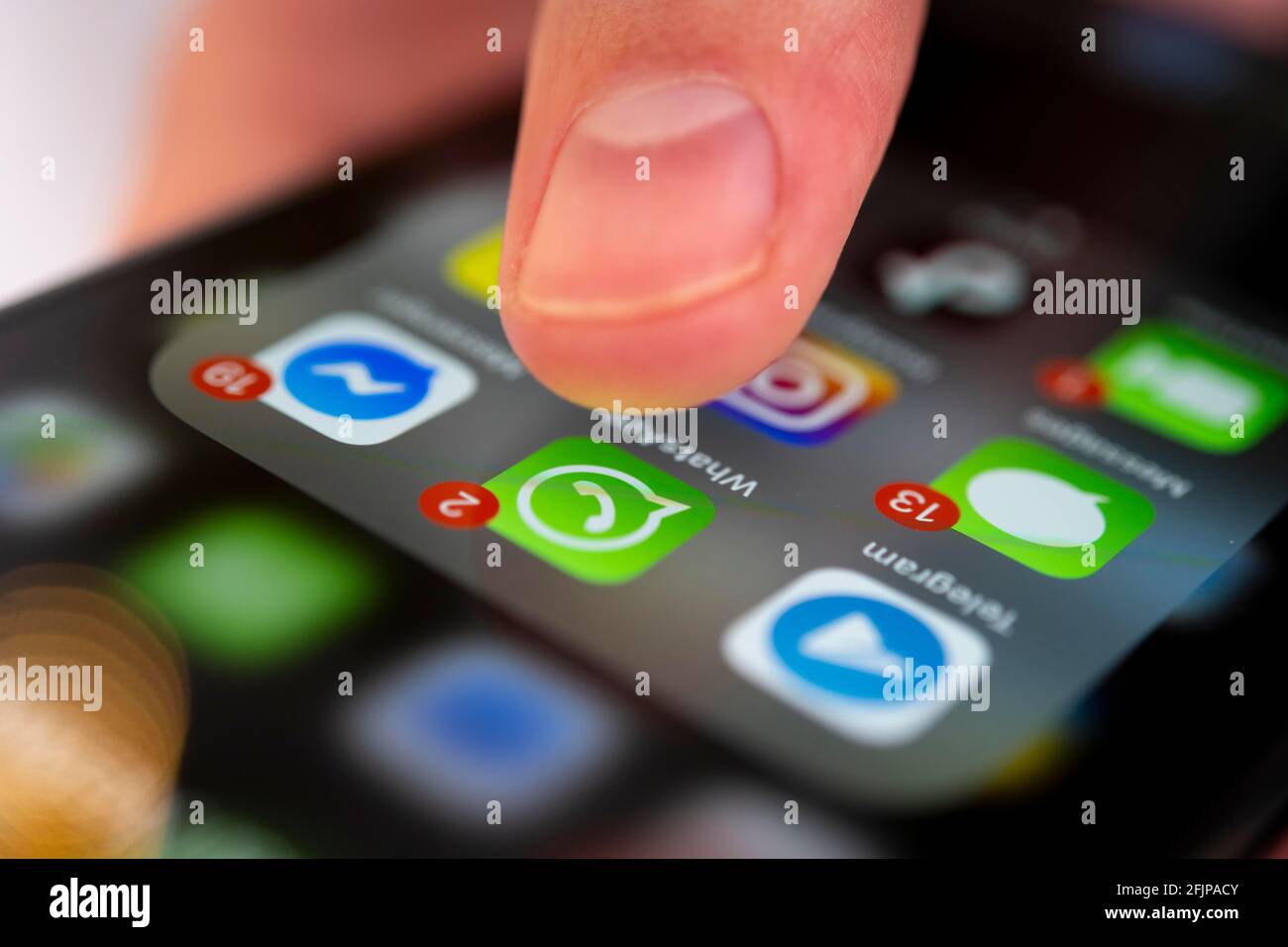 Finger tapping on screen with app icons of messenger services and ...
