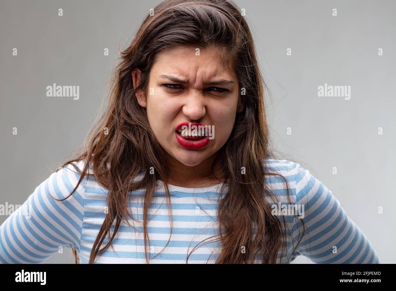 Angry young woman gnashing her teeth and glaring at the camera with a ...