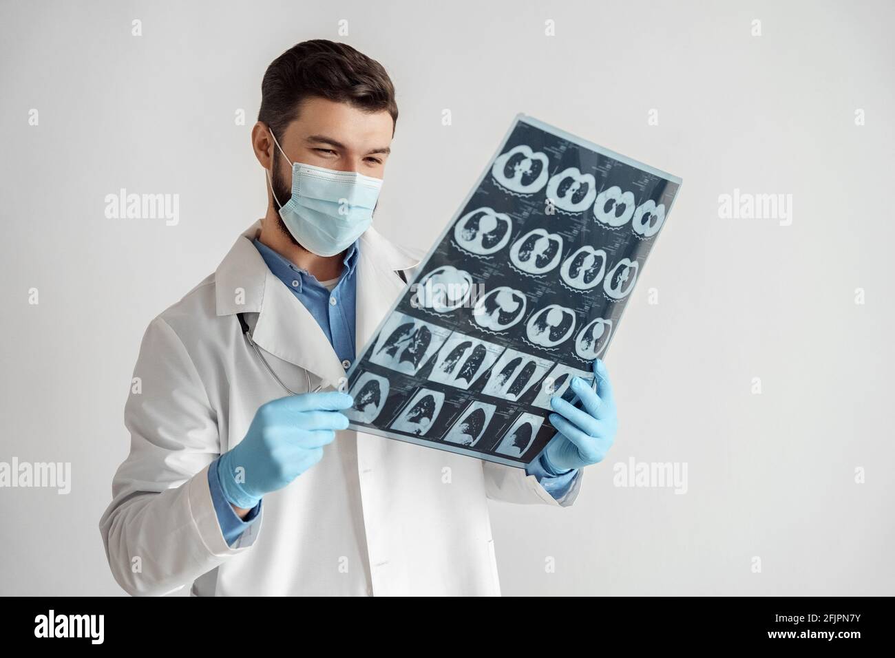 Smiling man doctor in face mask analyzing lungs x-ray MRI scan view ...