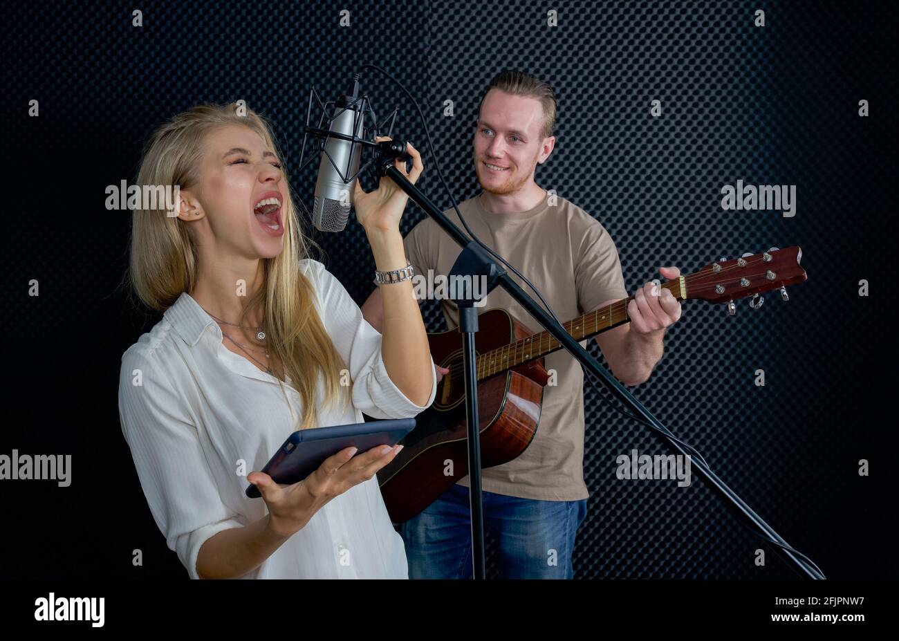 Young female singing with tablet computer in her hand. While the man ...