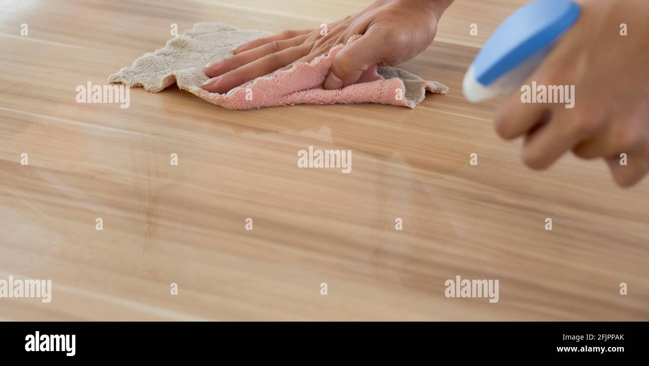 Closeup waiter's hand use a liquid cleaner and a towel to wipe off the ...