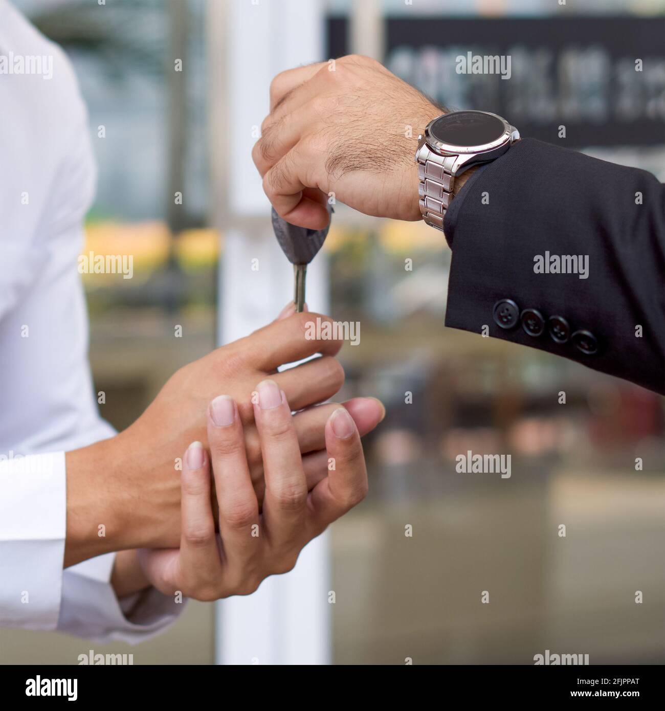 A businessman in a black suit handling car key to the valet service ...