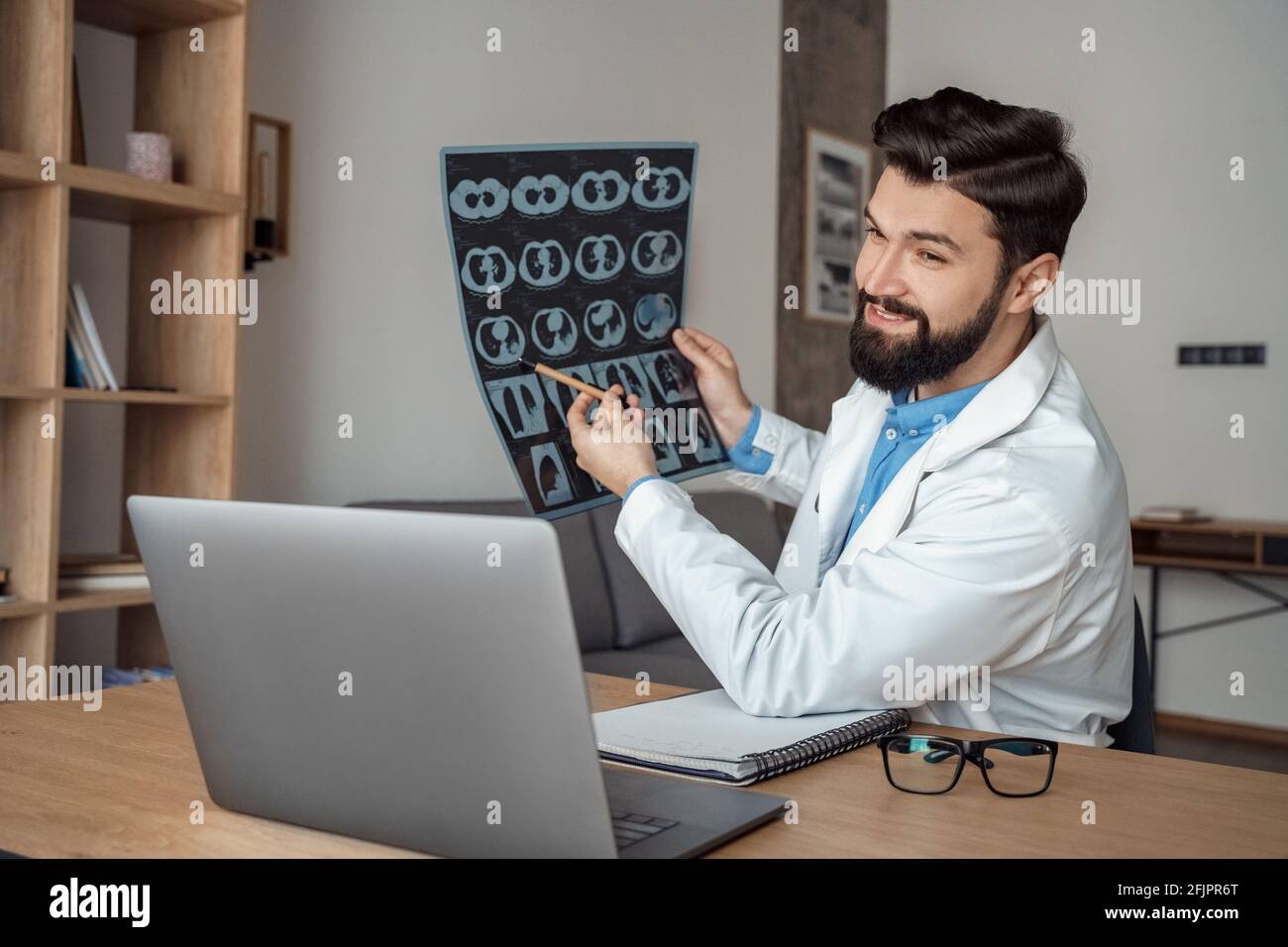 Caucasian male doctor with lungs scan sitting at desk and talking to ...
