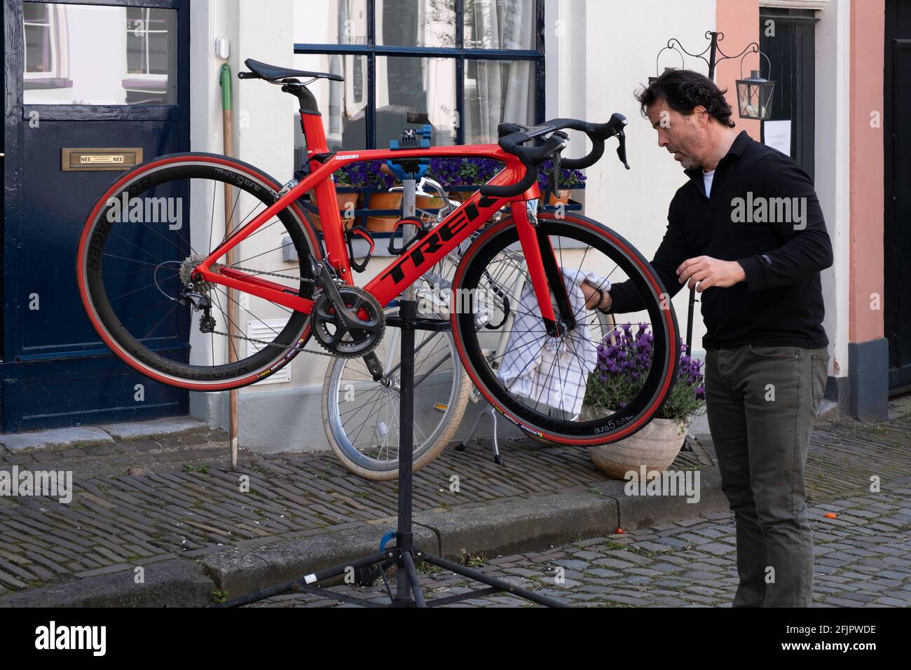 Red bicycle stands on a stand in front of a house on the street. A man ...