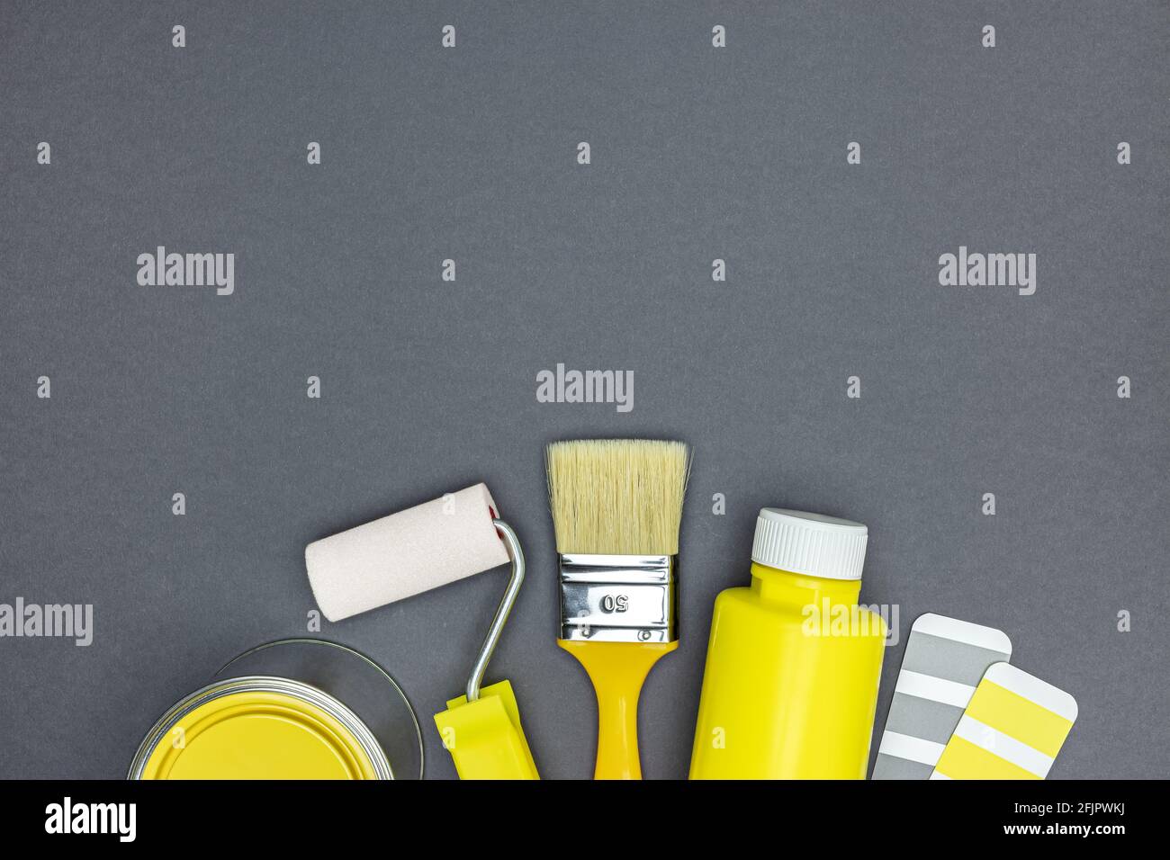 yellow paint tools with color sample and paint cans on dark background ...