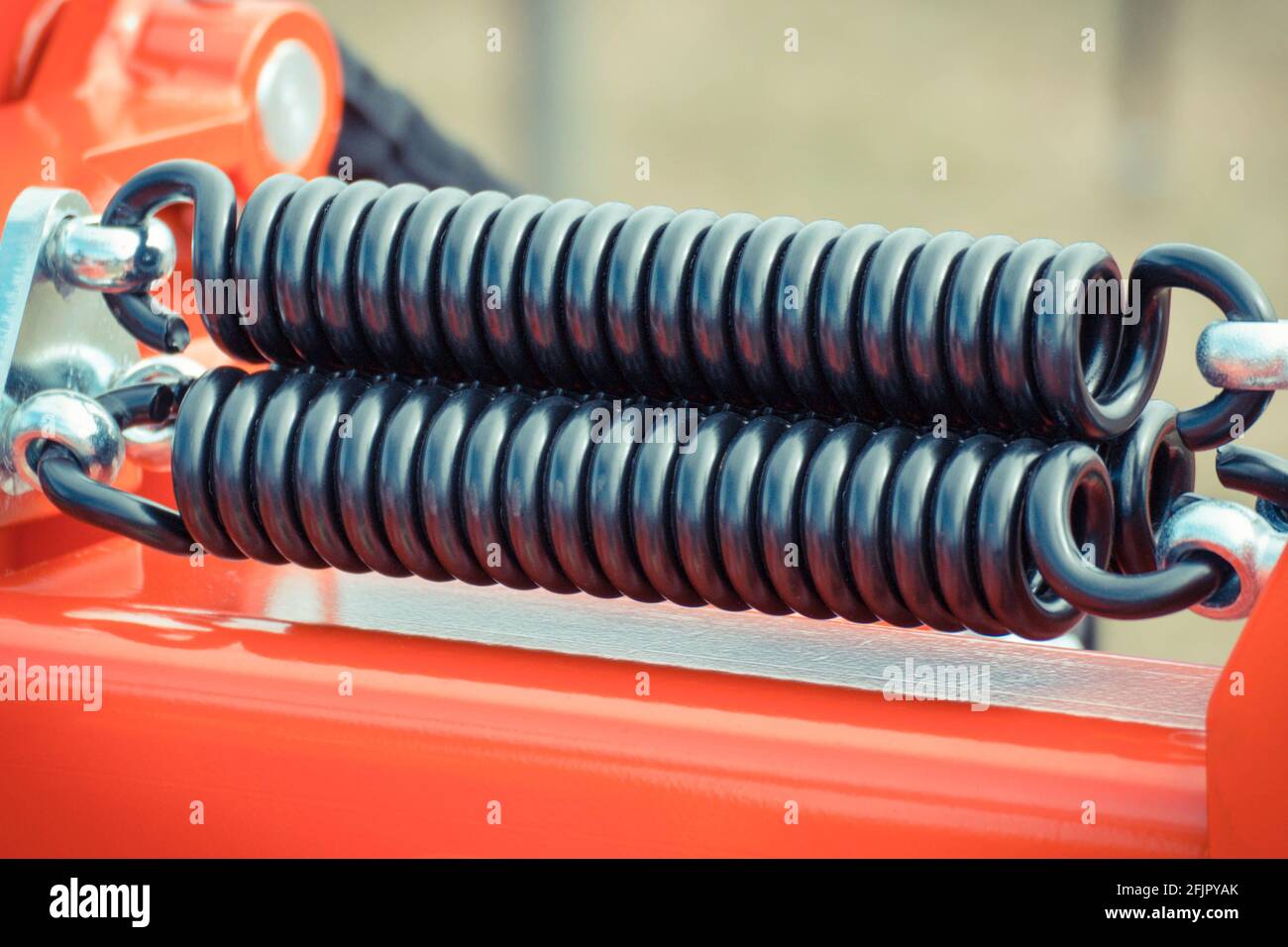 Hard black spring made of steel. Part of big industrial or agricultural ...