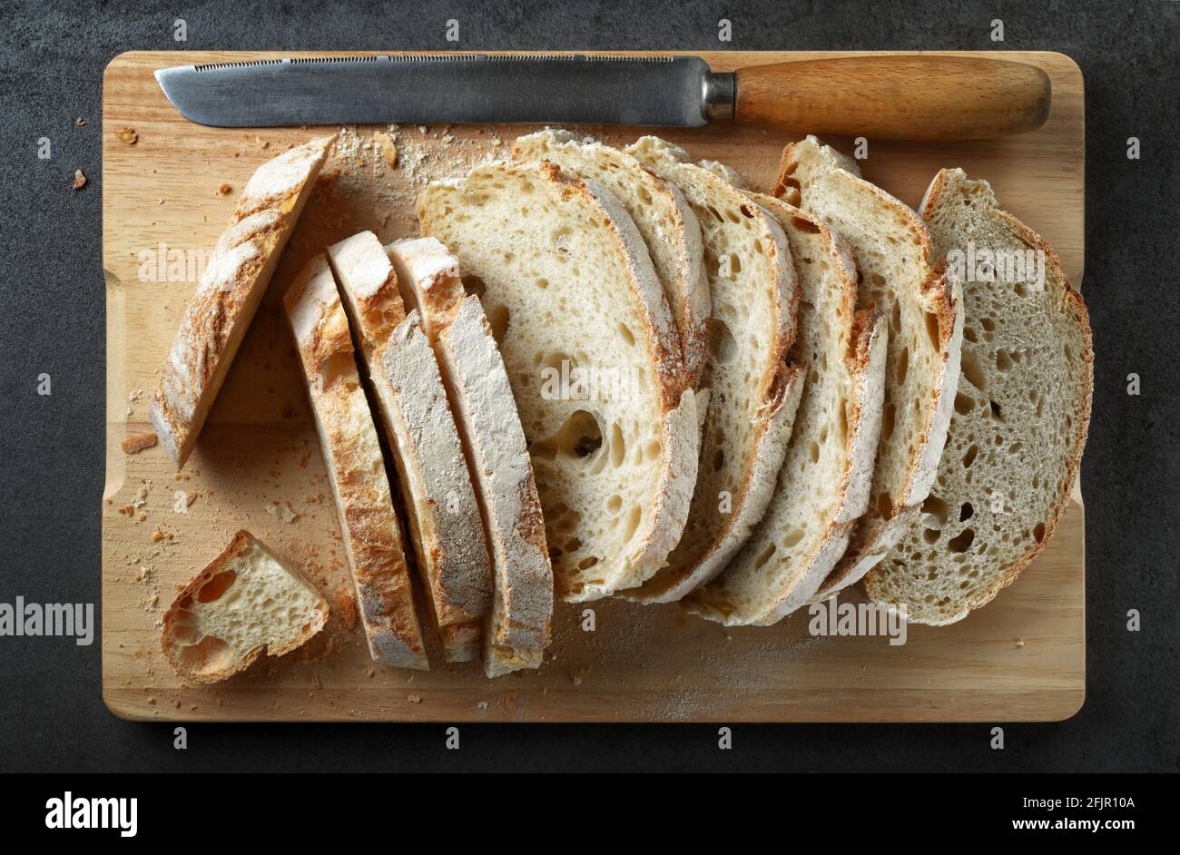 Traditional sliced bread loaf, with knife and cutting board, top view ...