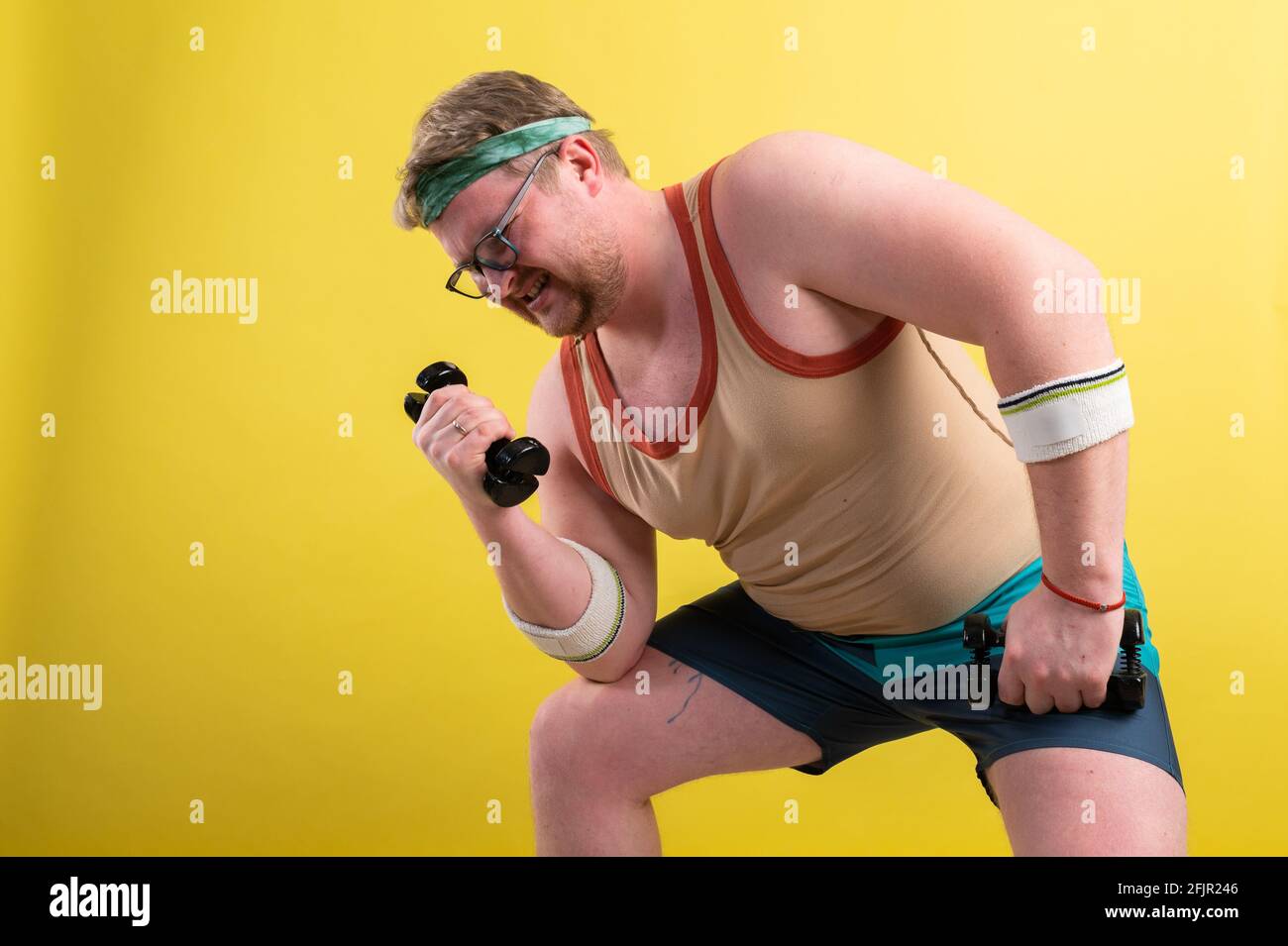Funny overweight man flexing his muscle isolated on yellow background ...