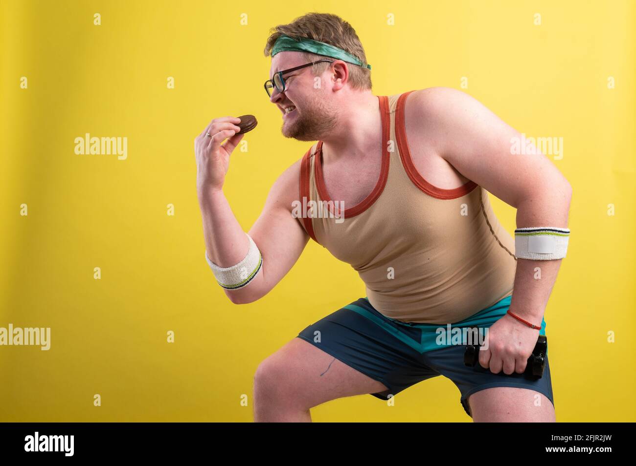 an overweight man plays sports on a yellow background. Funny fat man ...