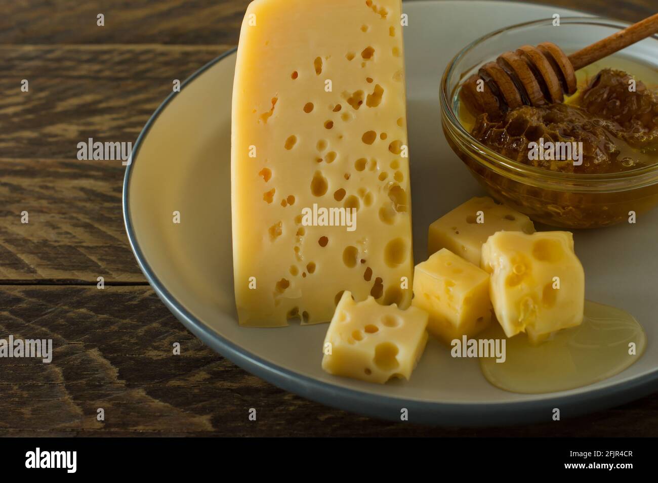 Radamer cheese on a plate served with honey. triangular piece of yellow ...