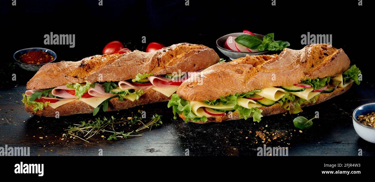Wide angle of yummy crunchy sub sandwiches placed on black table near ...