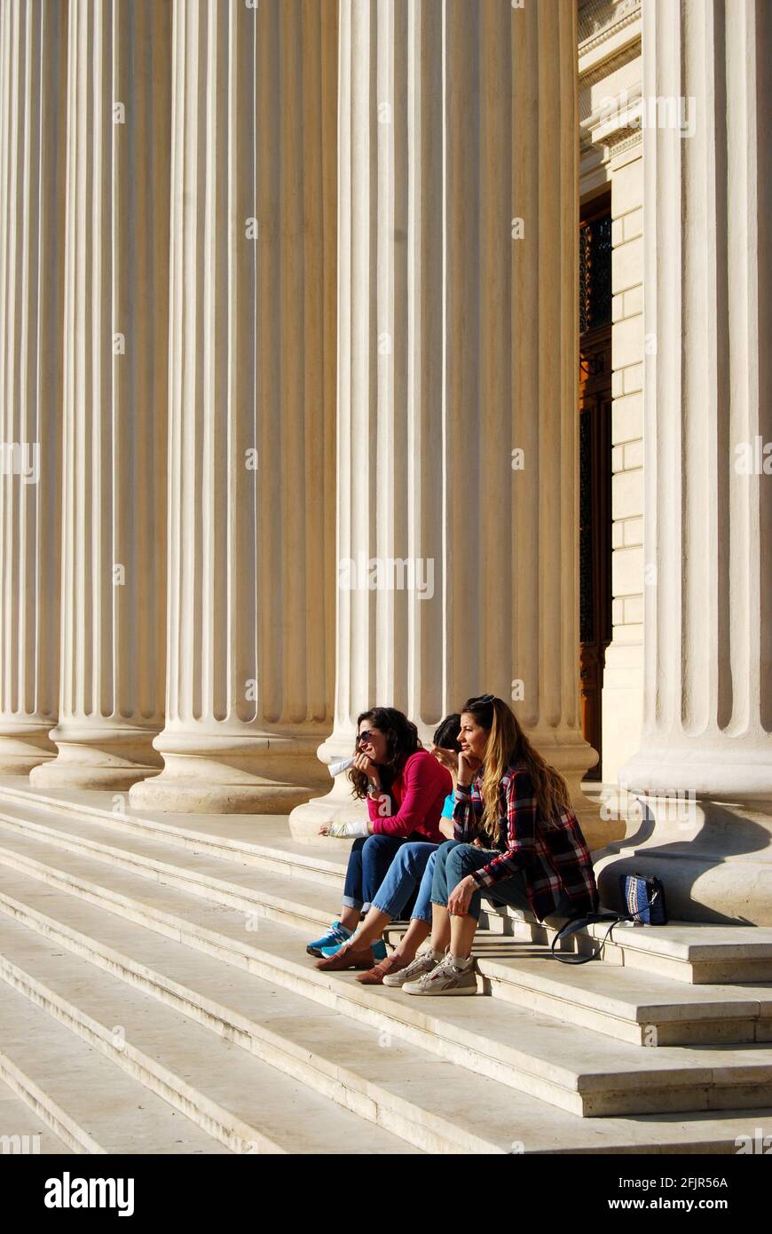 Bucharest Romania. Girls sitting on the steps of the Ateneul Roman ...