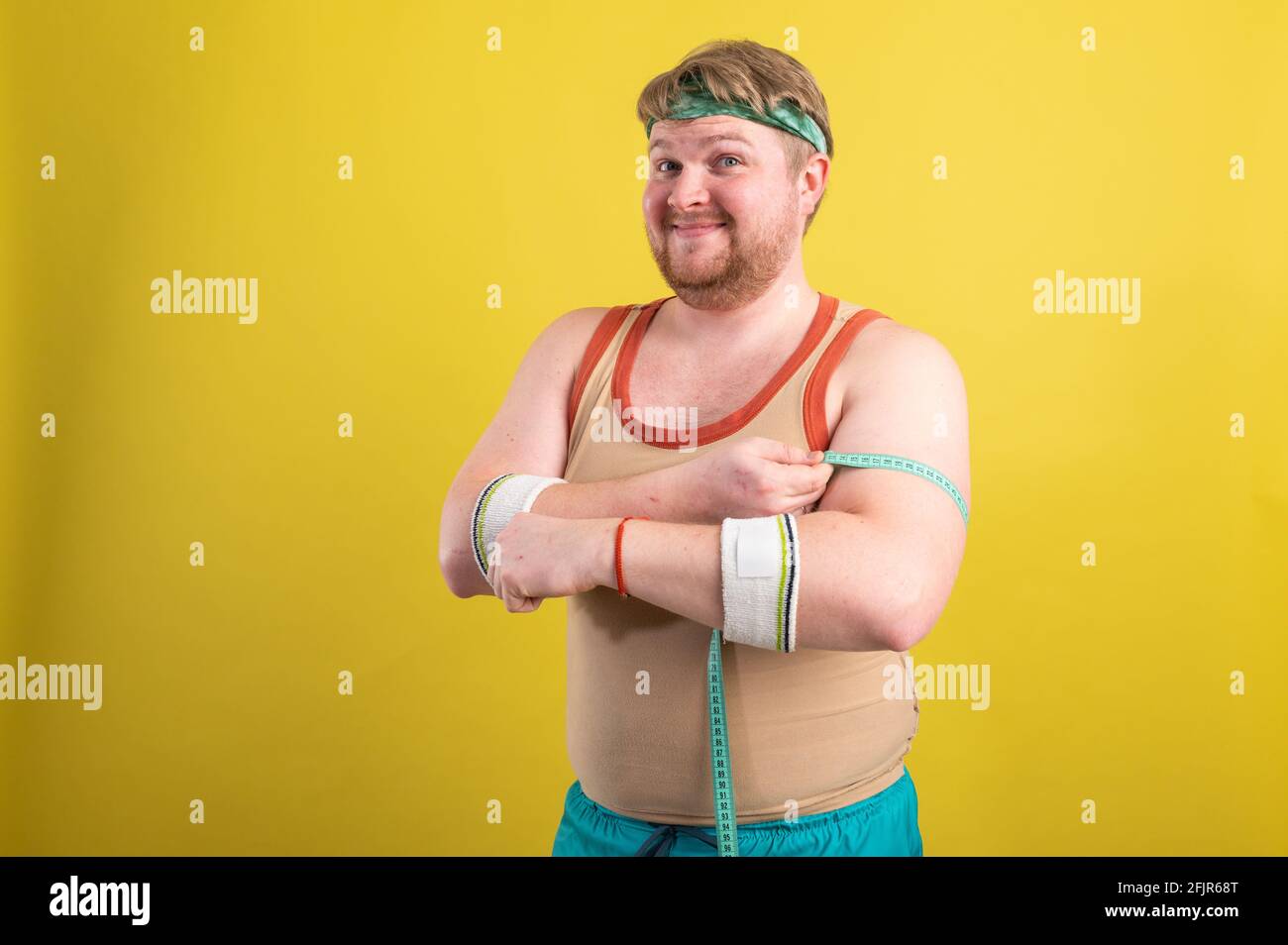 Funny overweight man flexing his muscle isolated on yellow background ...