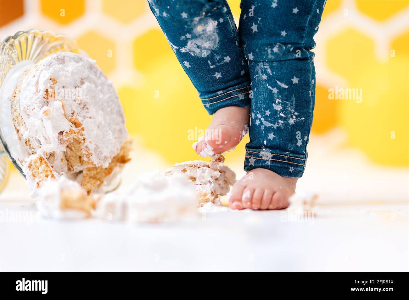Birthday. A small child's feet smeared in cream, and a cake lying on ...