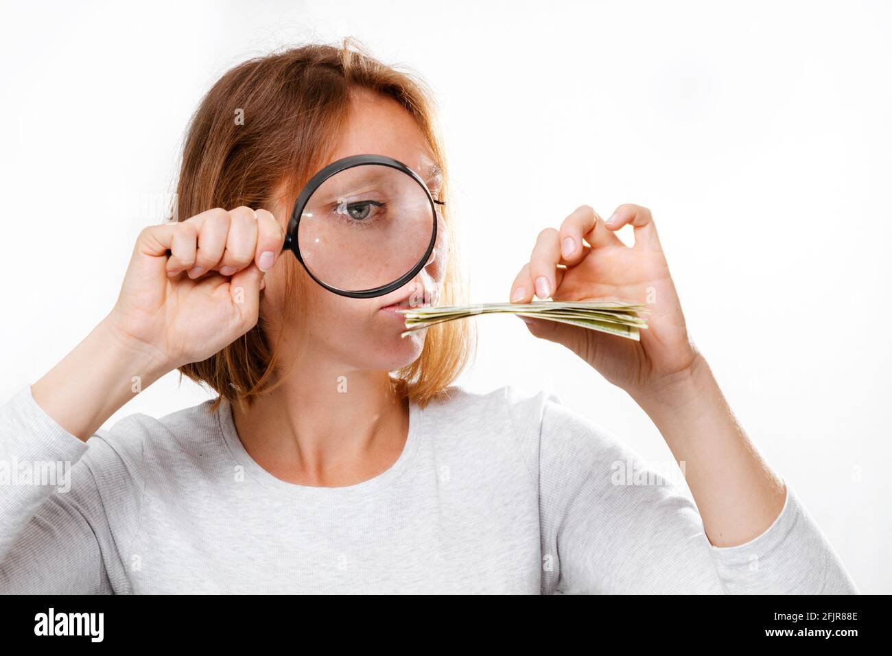 Portrait of a considerate woman looking through a magnifying glass at a ...