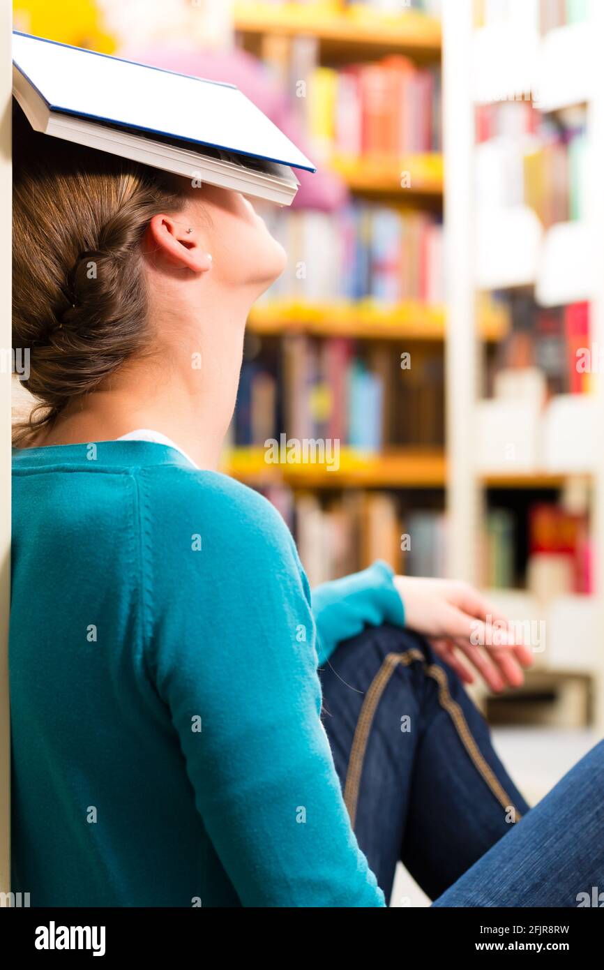 Student - Young woman in library with book learning, she is asleep ...