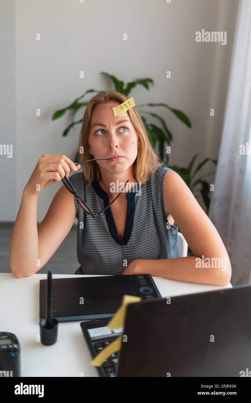 A young woman sitting at her Desk, holding glasses and thinking about ...
