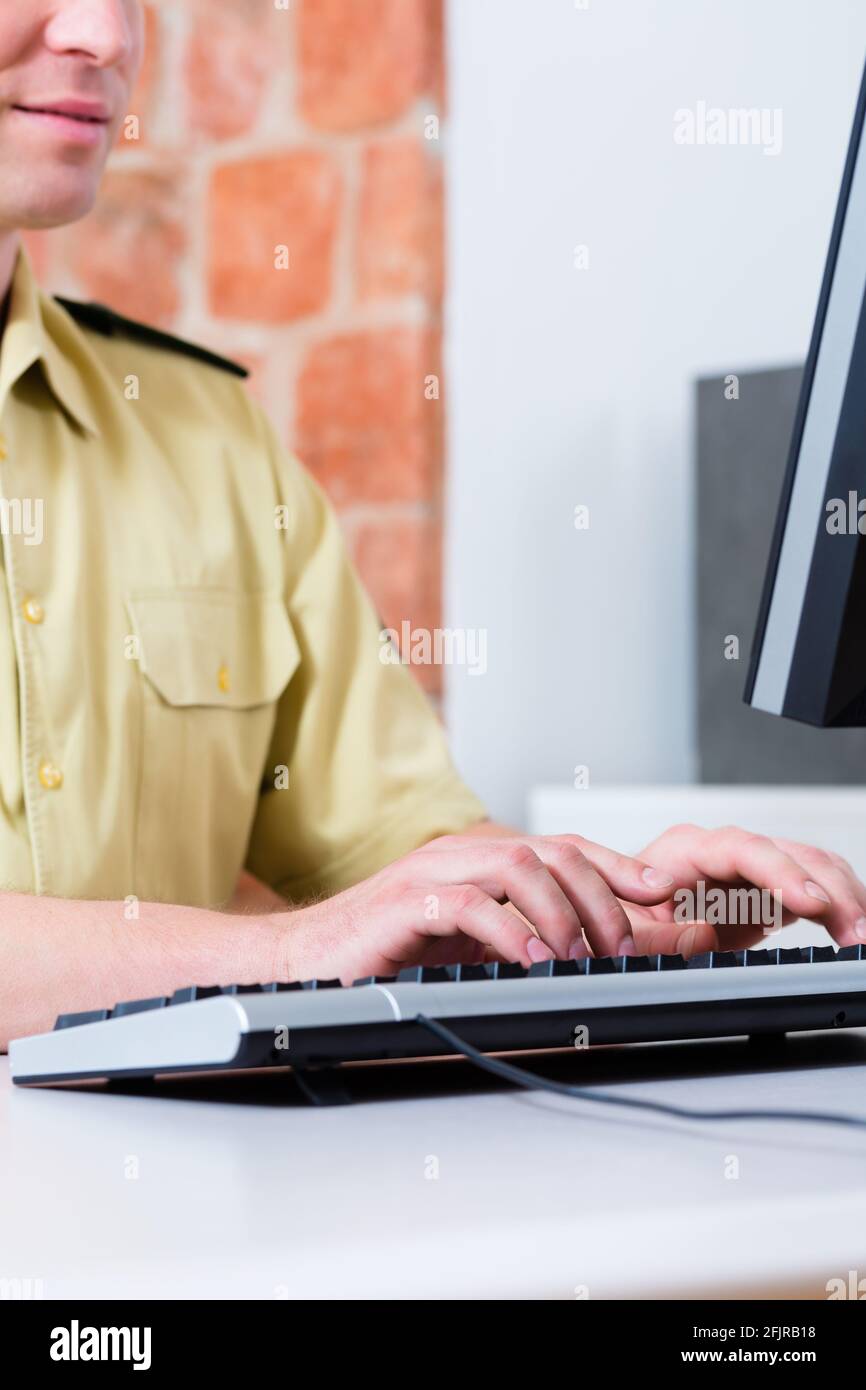 Police officer in police department working on the computer, on a case ...