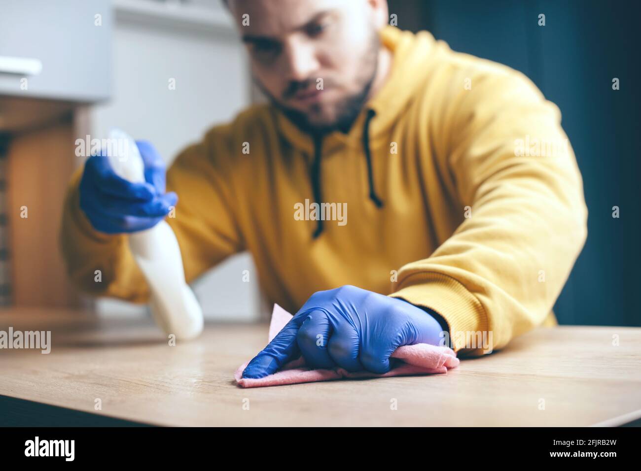 Close up photo of a concentrated man cleaning the table with a wipe and ...