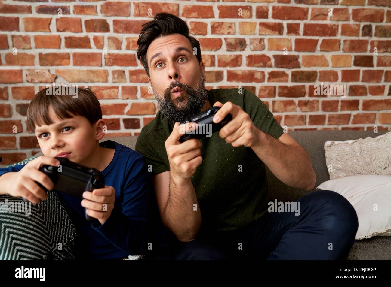 Focused father and son while playing video game Stock Photo - Alamy