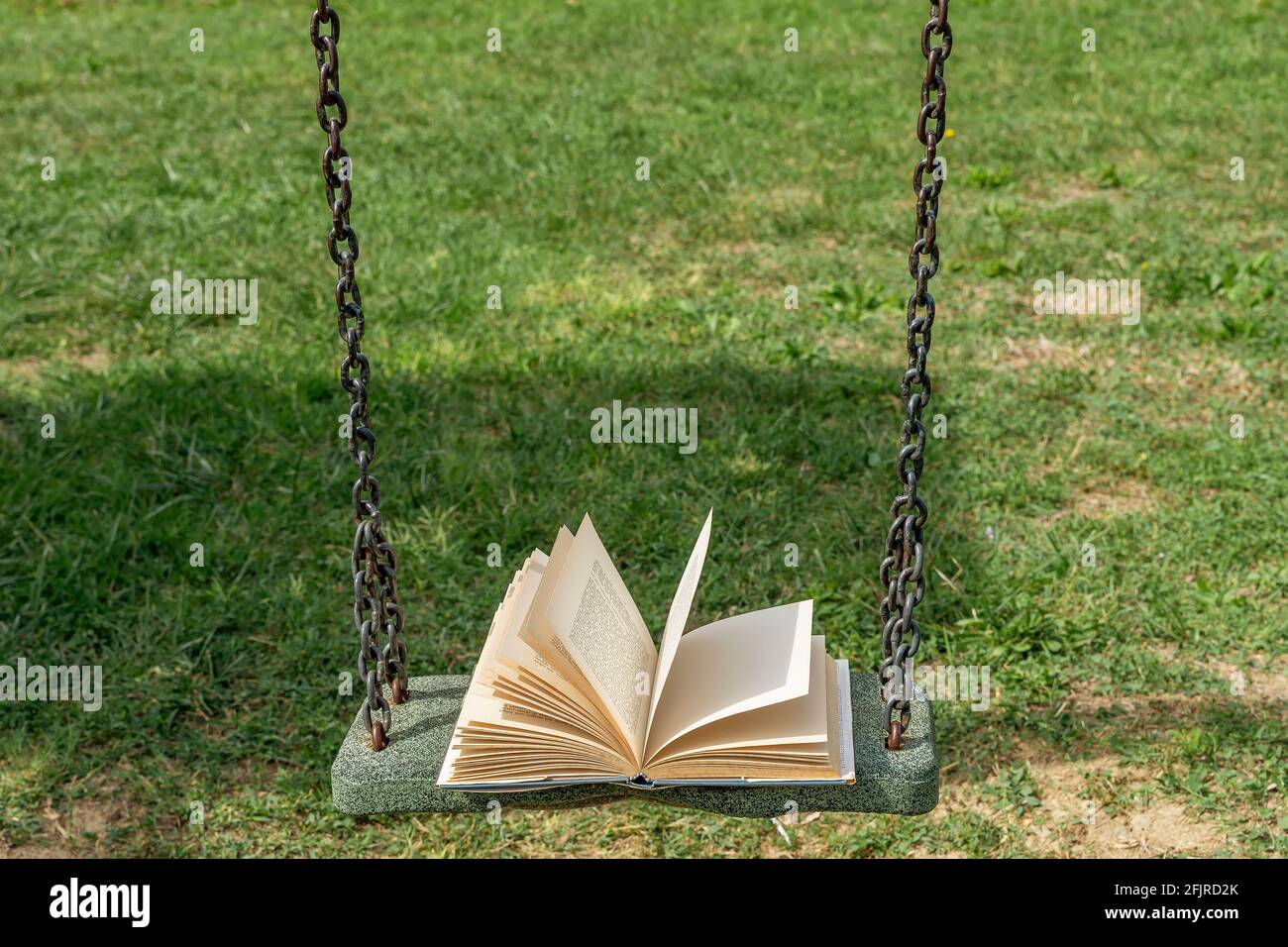 An open book with the pages blowing in the wind on a swing against a ...