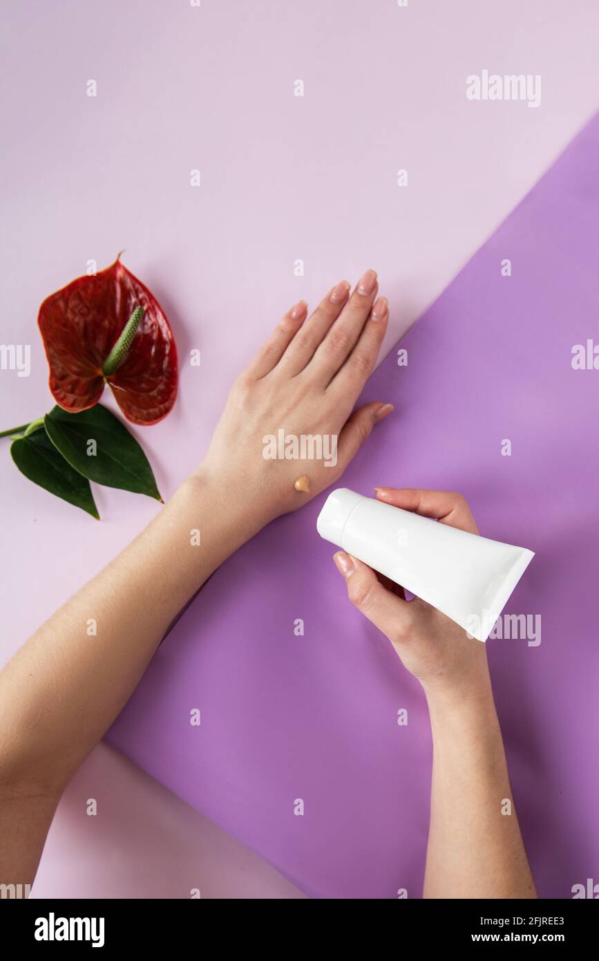 Young woman applying hand cream at color purple background Stock Photo ...