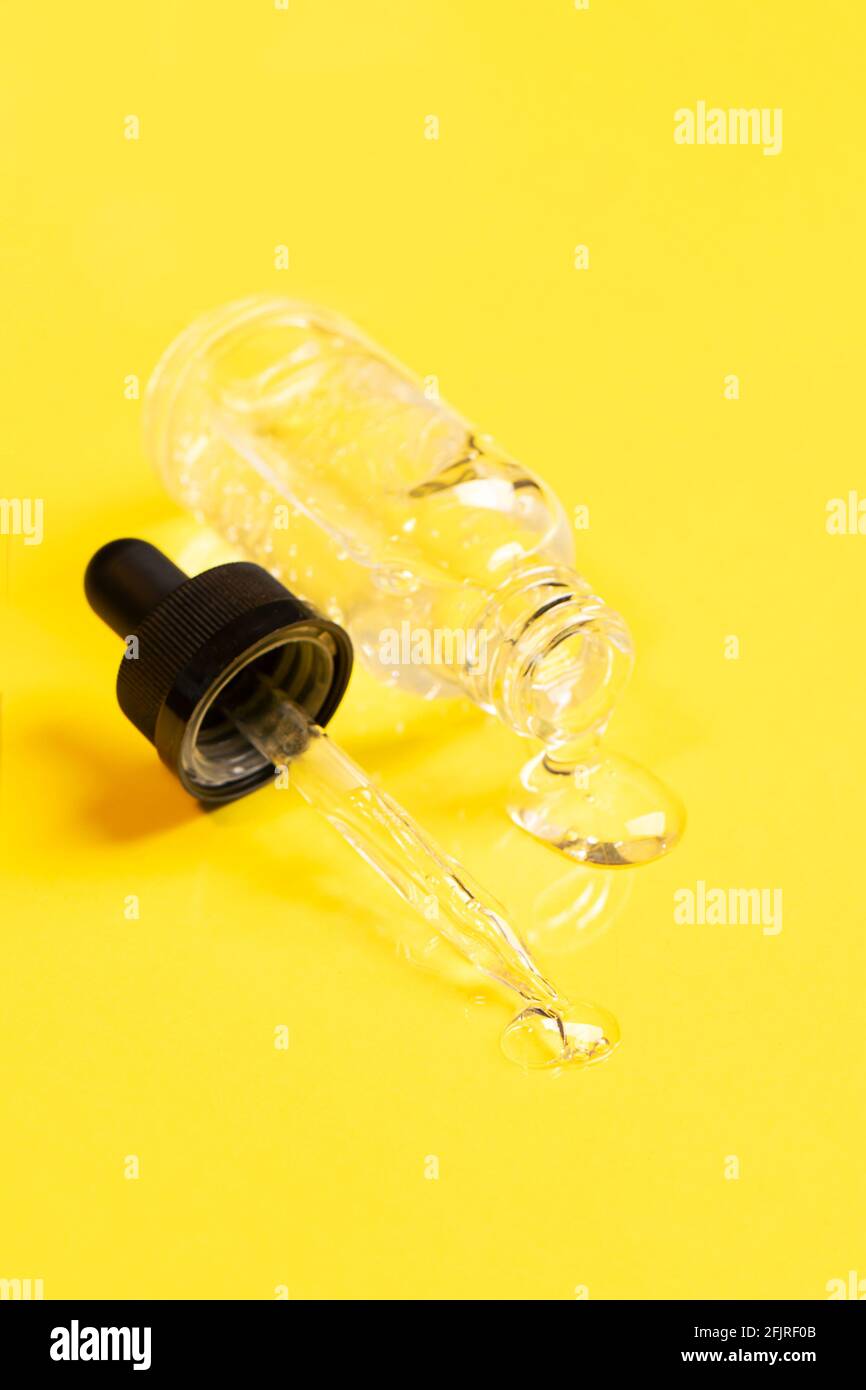 Cosmetic liquid gel serum lubricant flows out of a glass bottle and a ...