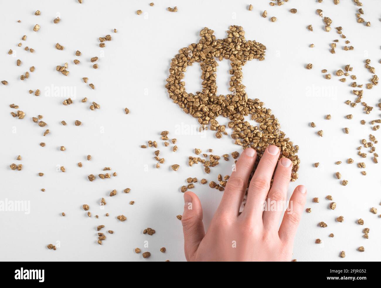 Hand sweeping away a dollar sign made from golden pieces Stock Photo ...