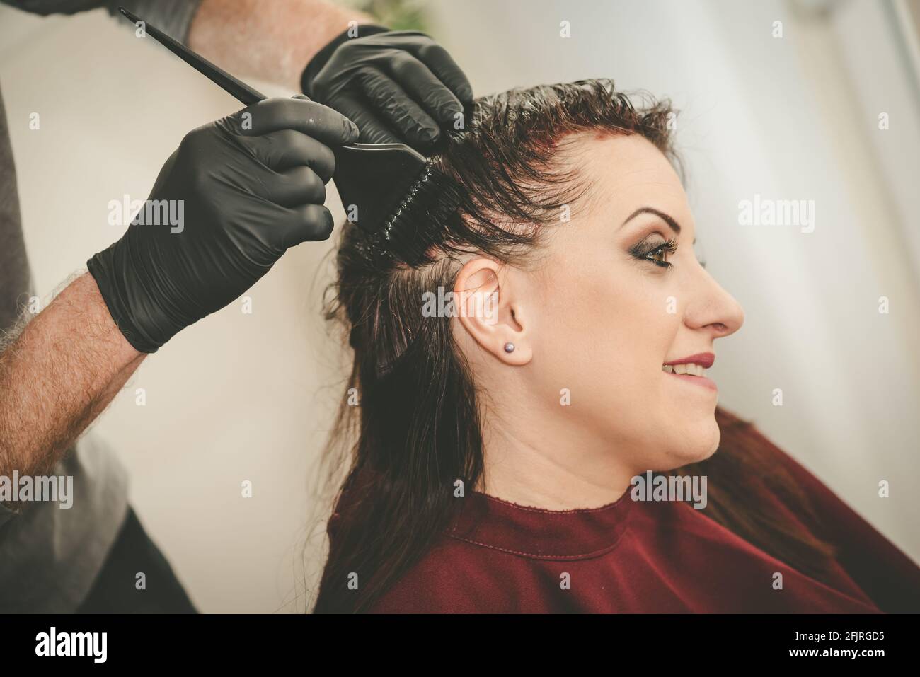 Hairdresser coloring female client hair Stock Photo - Alamy