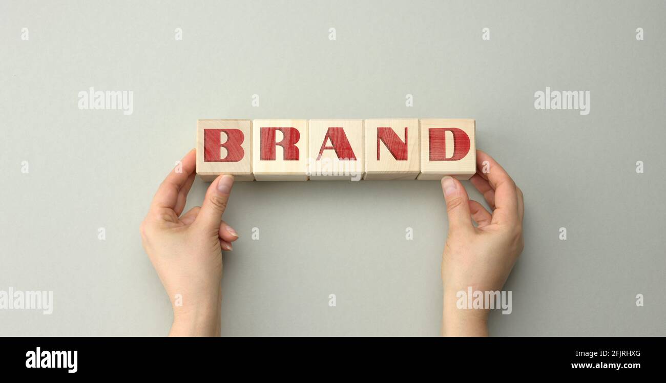 wooden blocks with the inscription brand and two female hands on a gray ...