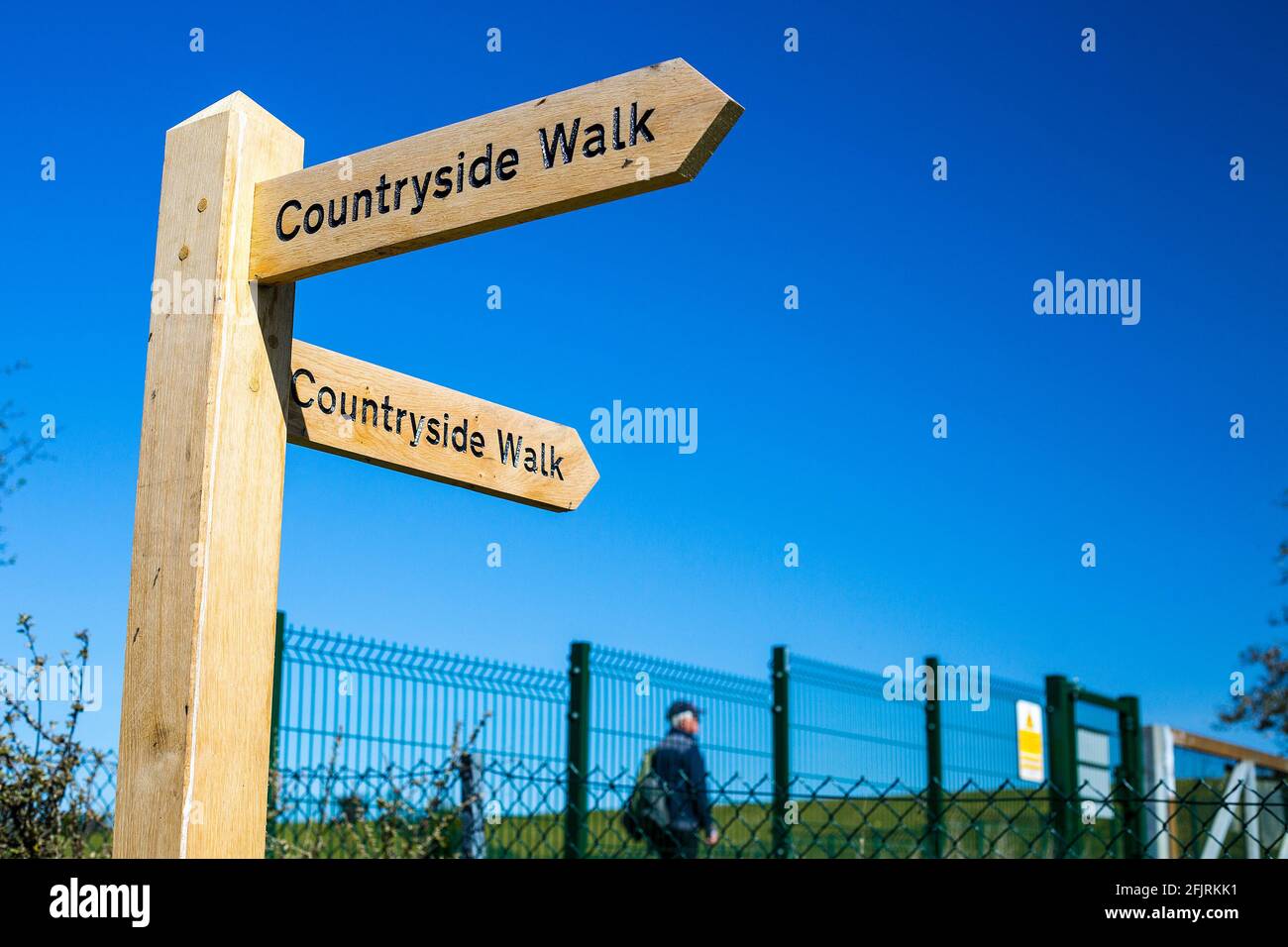 A signpost depicting countryside walks with a male walker in the ...