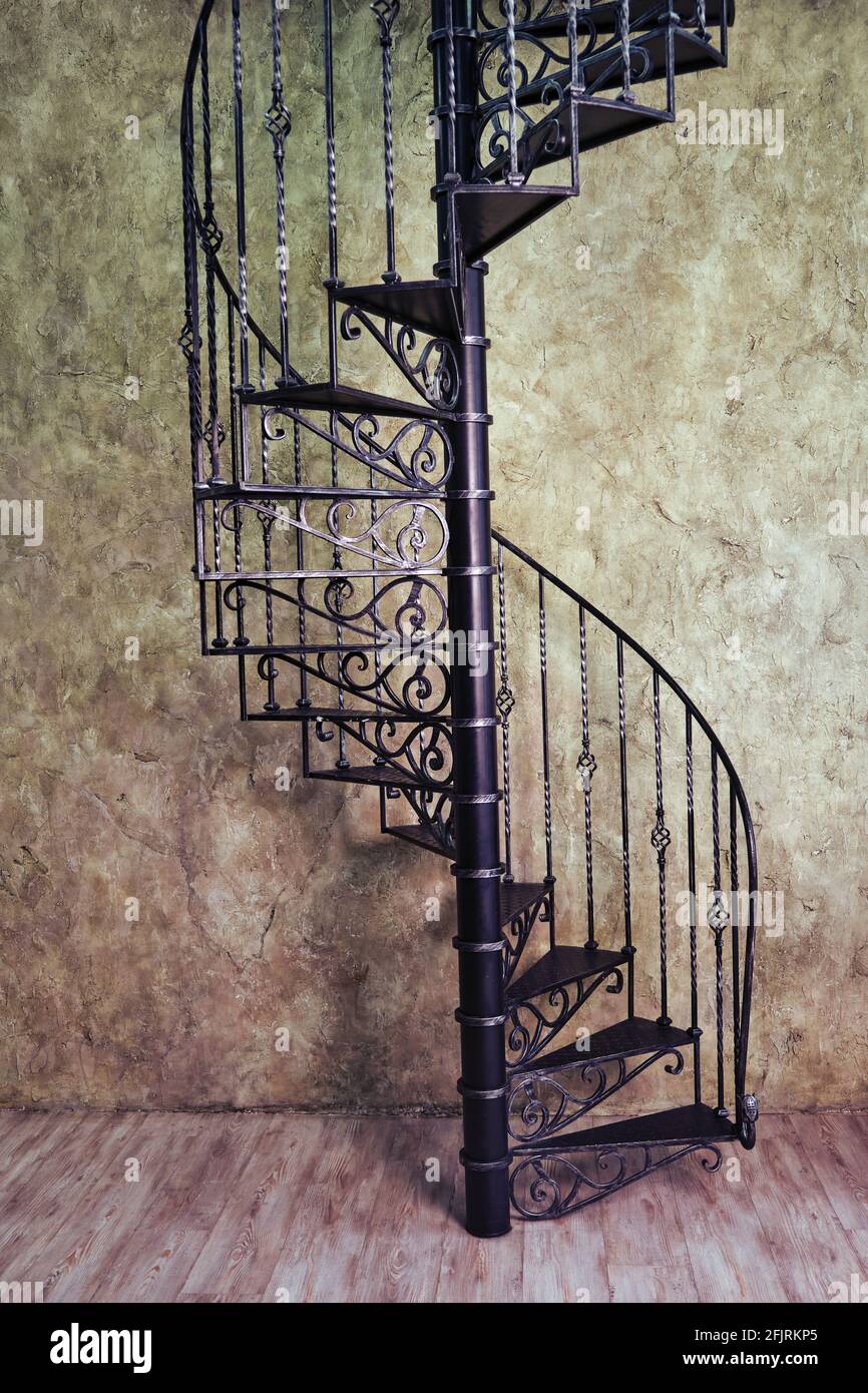 Vintage metal spiral staircase on the background of the old wall and ...