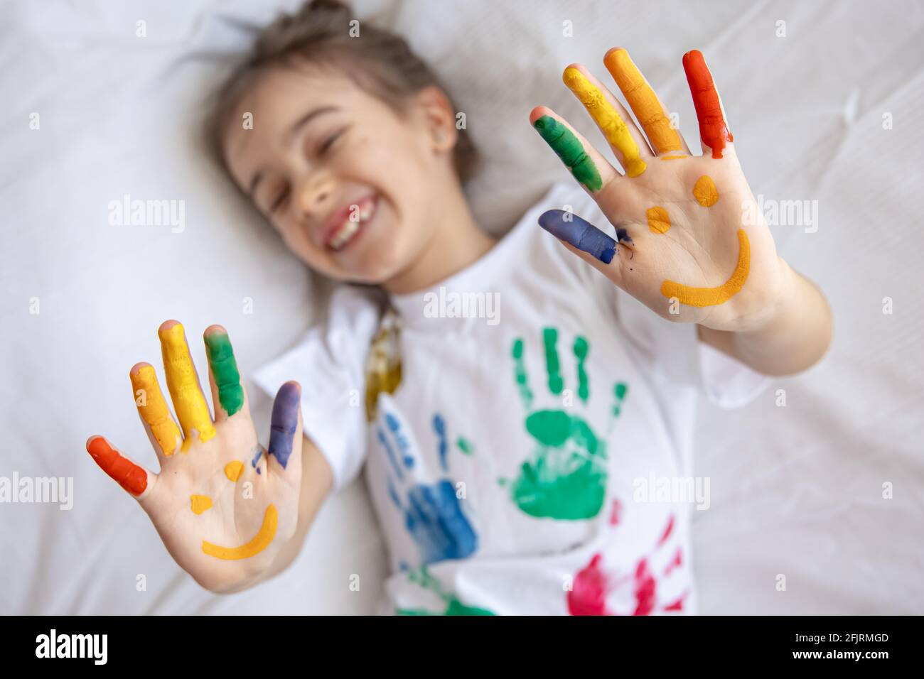Painted smiles on the palms of a little girl. Funny bright drawings on ...