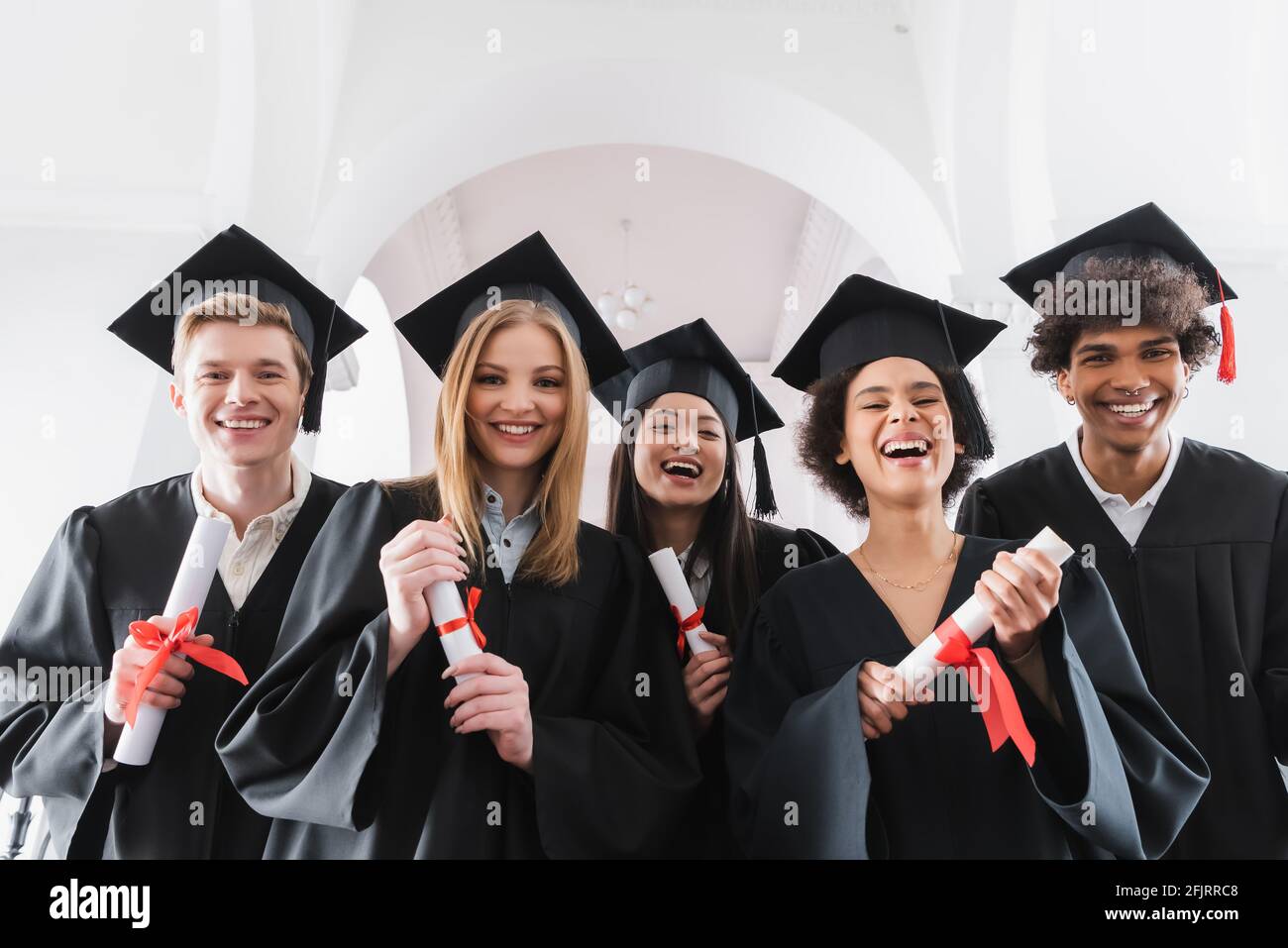 Positive multicultural students with diplomas smiling at camera Stock ...