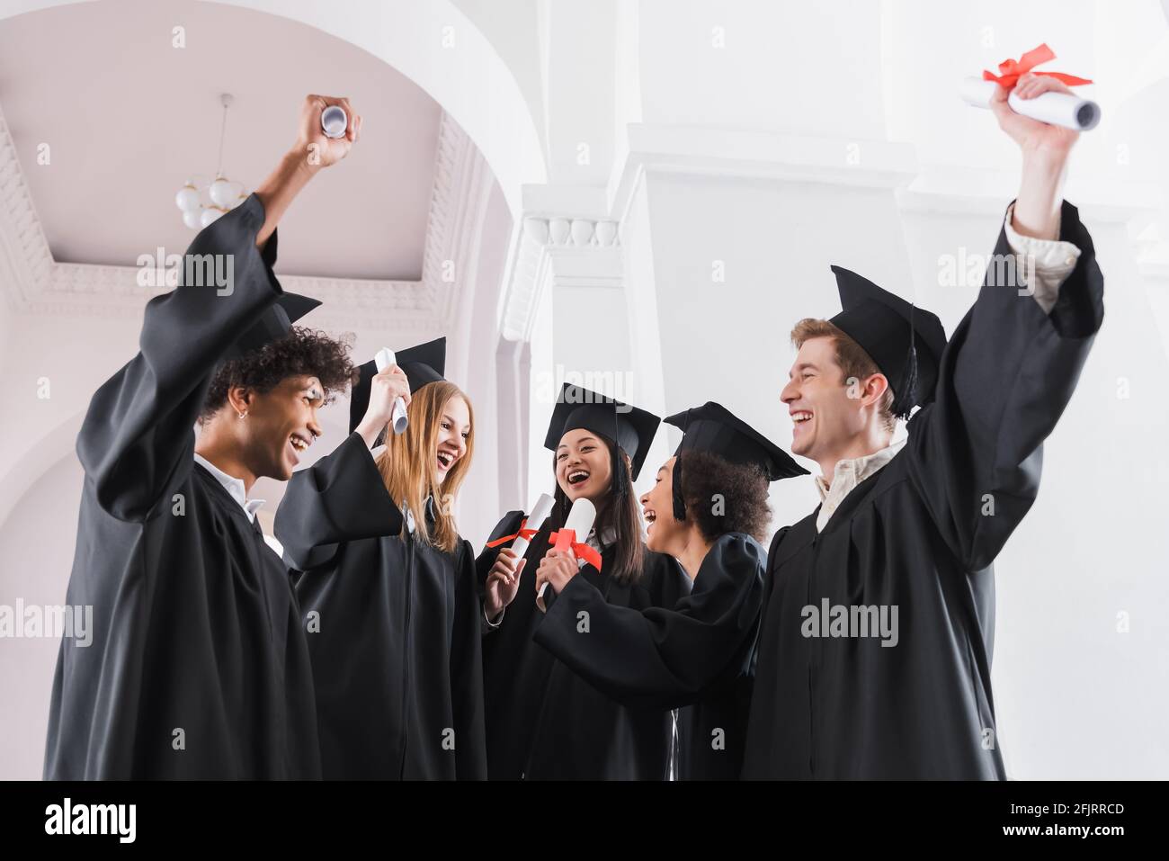 Cheerful multiethnic graduates with diplomas in university Stock Photo ...