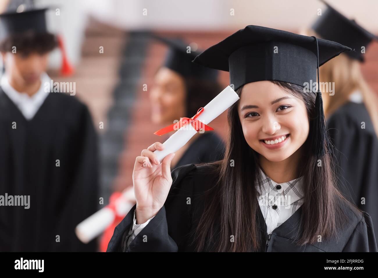 Asian graduate in cap smiling and holding diploma Stock Photo - Alamy