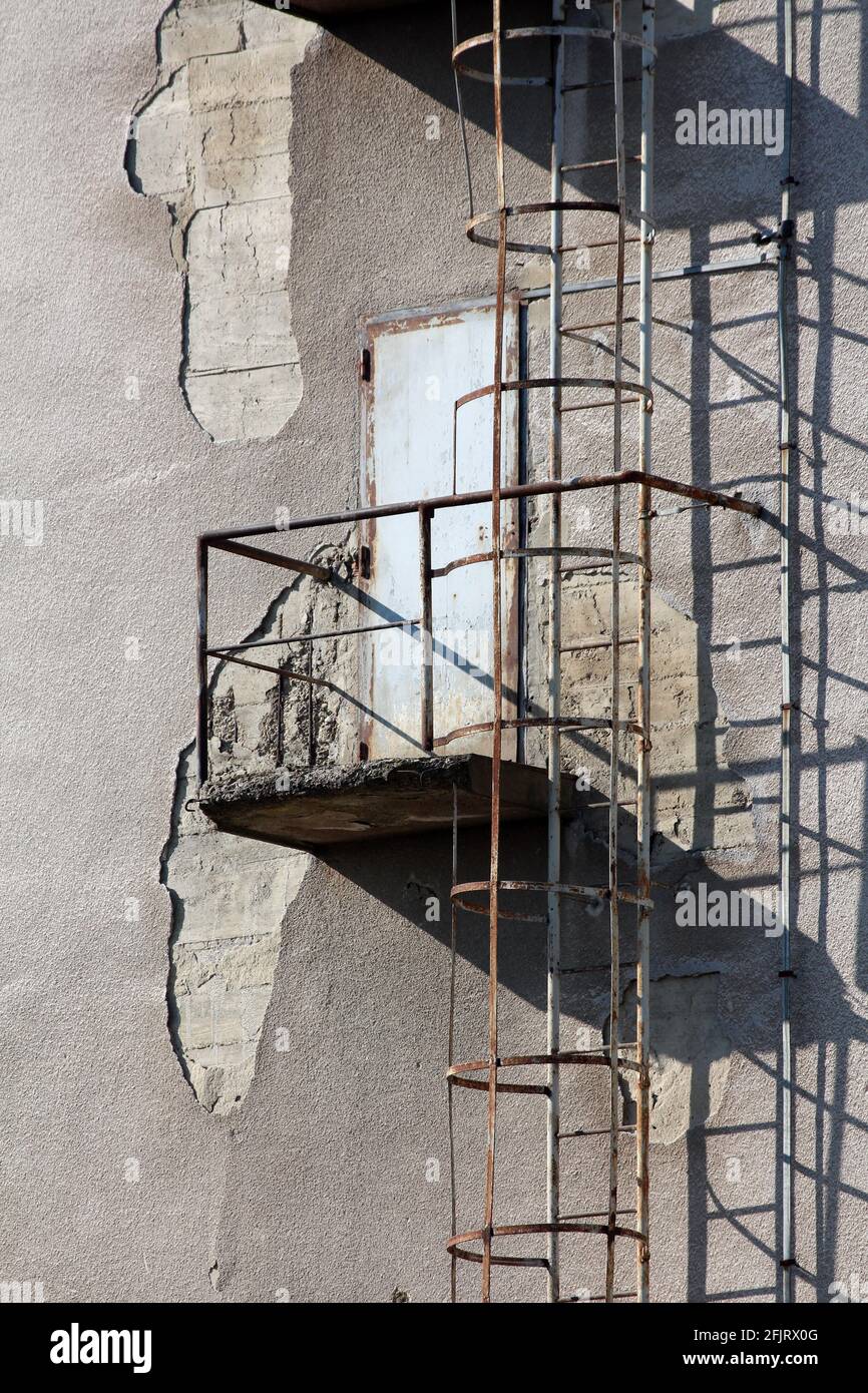 Rusted metal fire escape stairs with round steel safety tunnel mounted ...