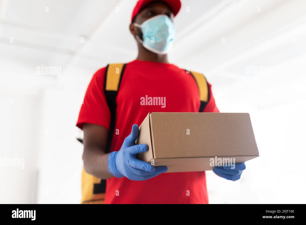 Black delivery man in medical mask giving box Stock Photo - Alamy